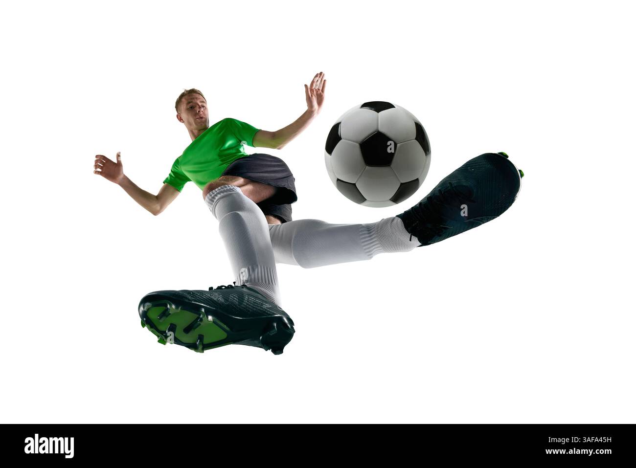Low angle of male athlete, mid-air jump with extended leg striking ball ...