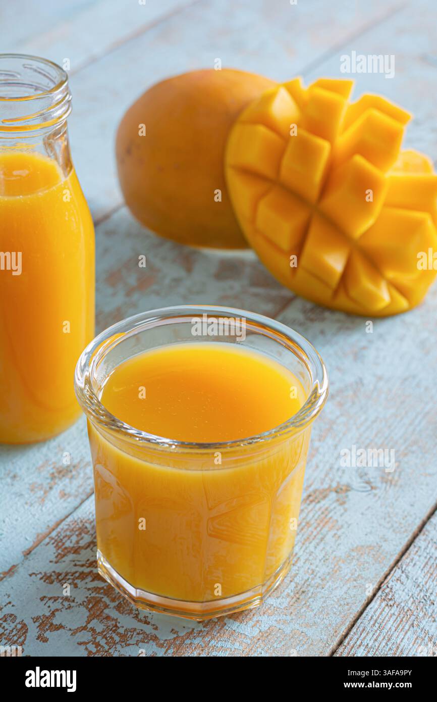 Fresh mango juice in a glass glass with mango slice on blue wooden ...