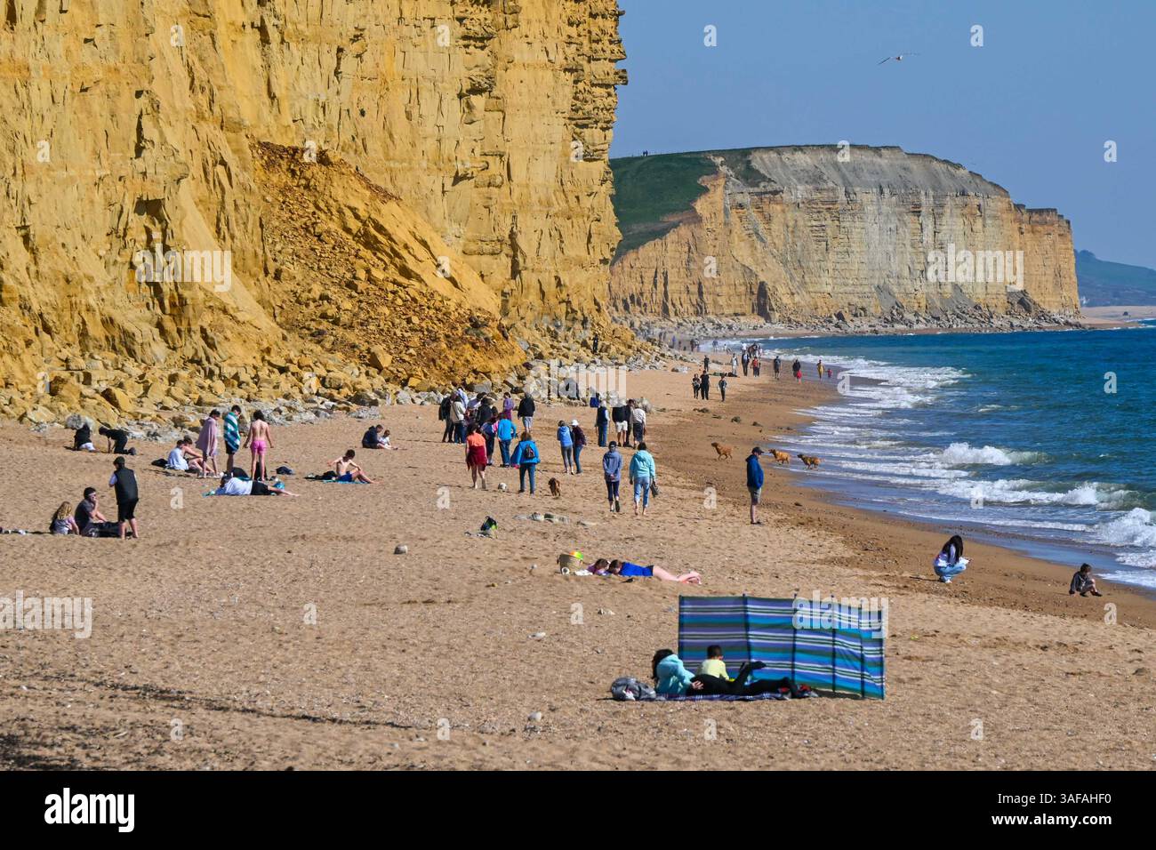 West Bay, Dorset, UK. 7th April 2025. UK Weather. Beachgoers enjoying ...