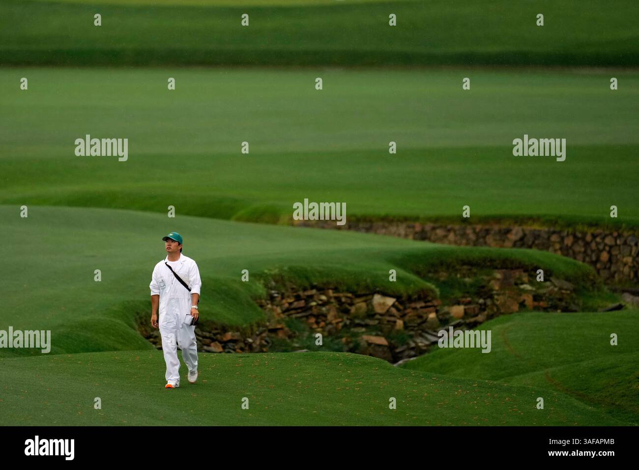 Shota Hayafuji, caddie for Hideki Matsuyama, of Japan, walks on the ...