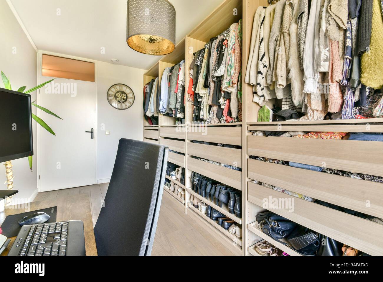A stylish organized closet featuring rows of neatly arranged clothing ...