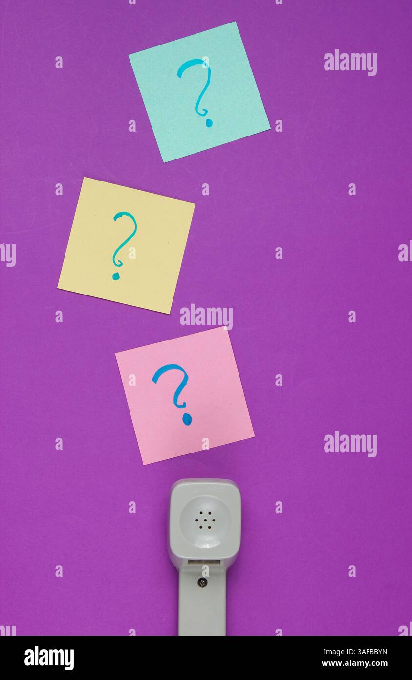 Retro handset and question marks on memo pieces of paper. Call center ...