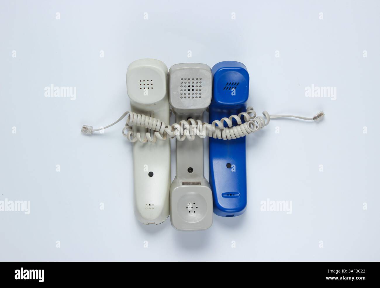 Three office phone tubes wrapped in cable on a white studio background ...