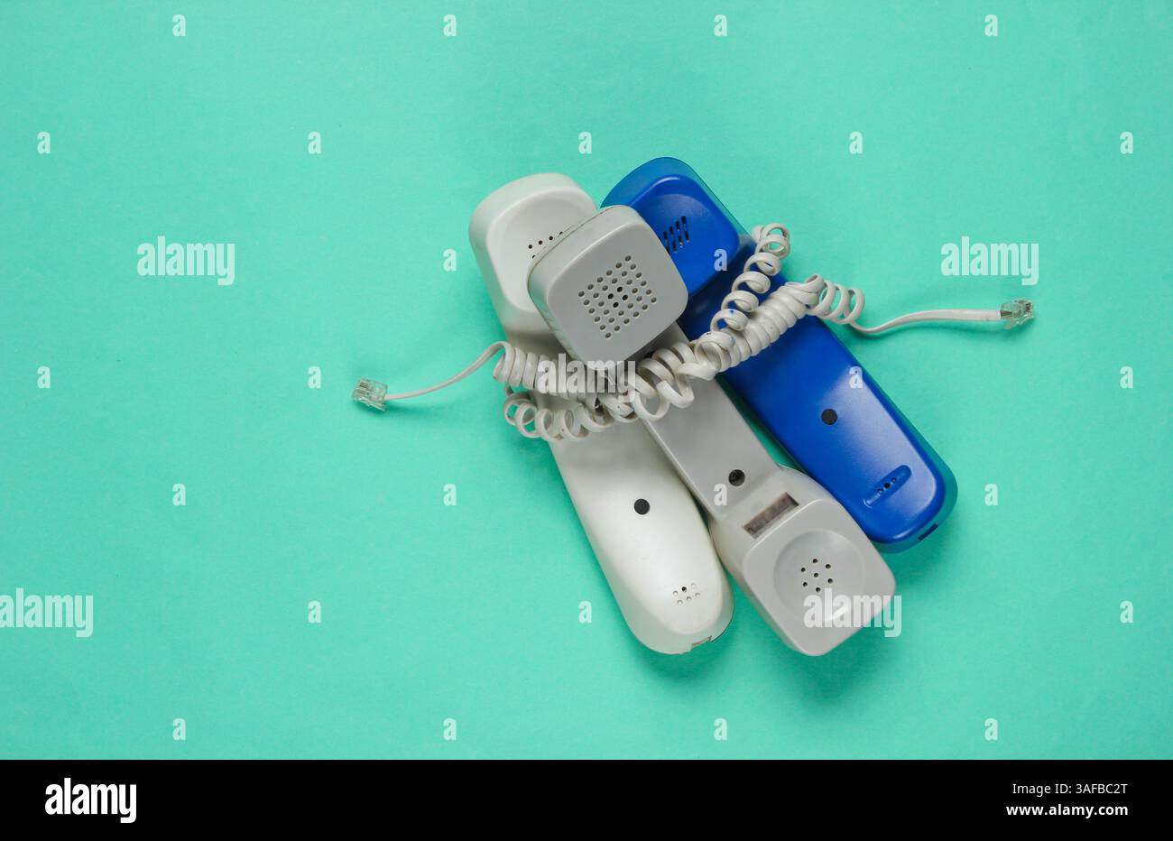 Three office phone tubes wrapped in cable on blue studio background ...