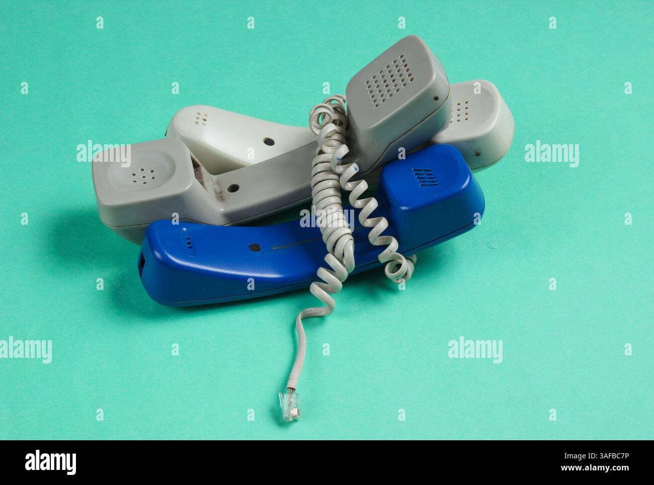 Three office phone tubes wrapped in cable on blue studio background ...
