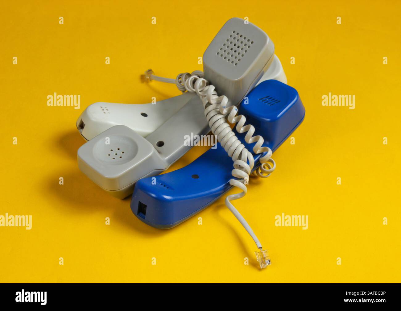 Three office phone tubes wrapped in cable on blue studio background ...