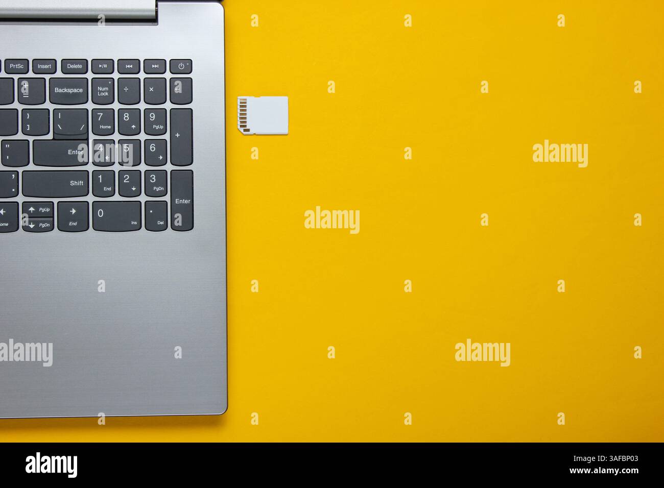 Laptop and SD memory card on yellow paper background. Modern gadgets ...