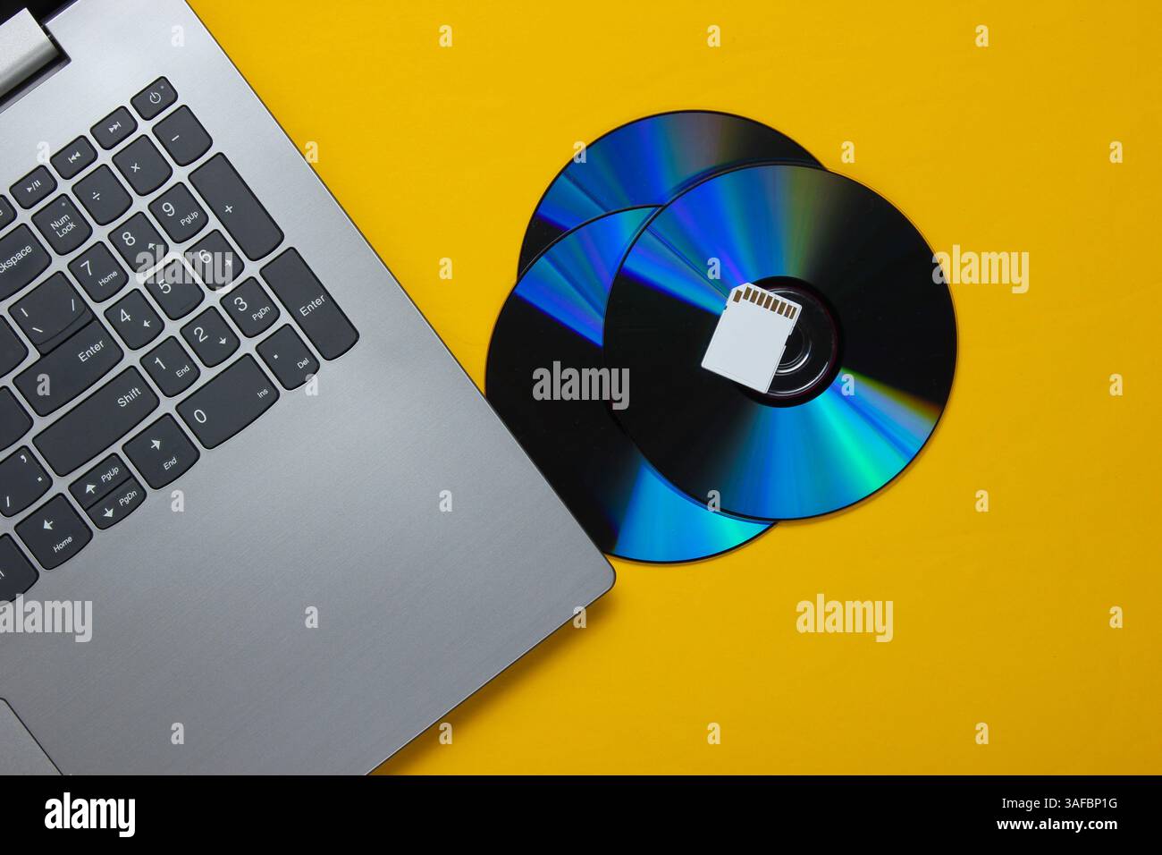 Laptop, SD memory card, cd drives on yellow paper background. Modern ...