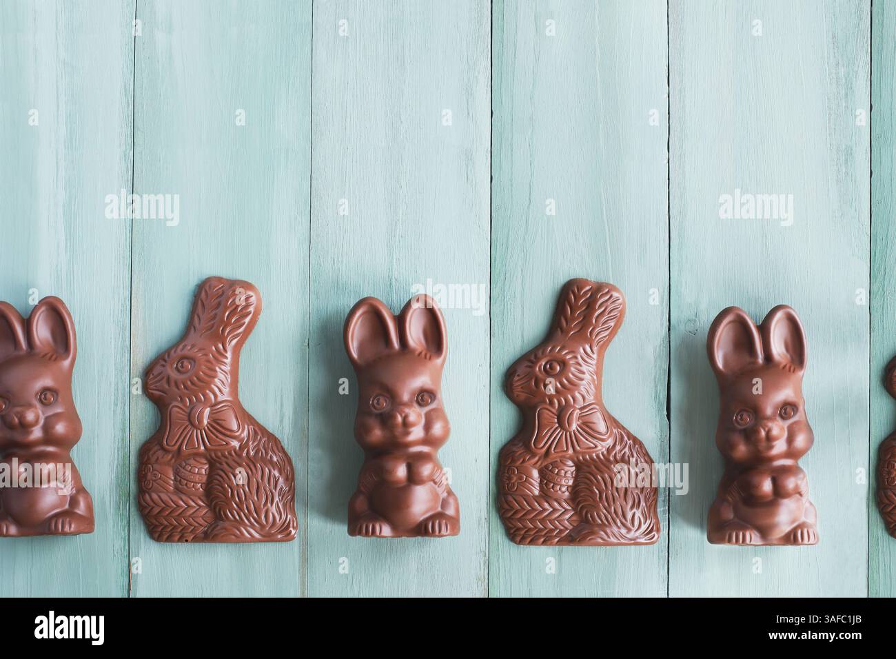 Flatlay of cute chocolate bunny rabbits over a mint green background ...