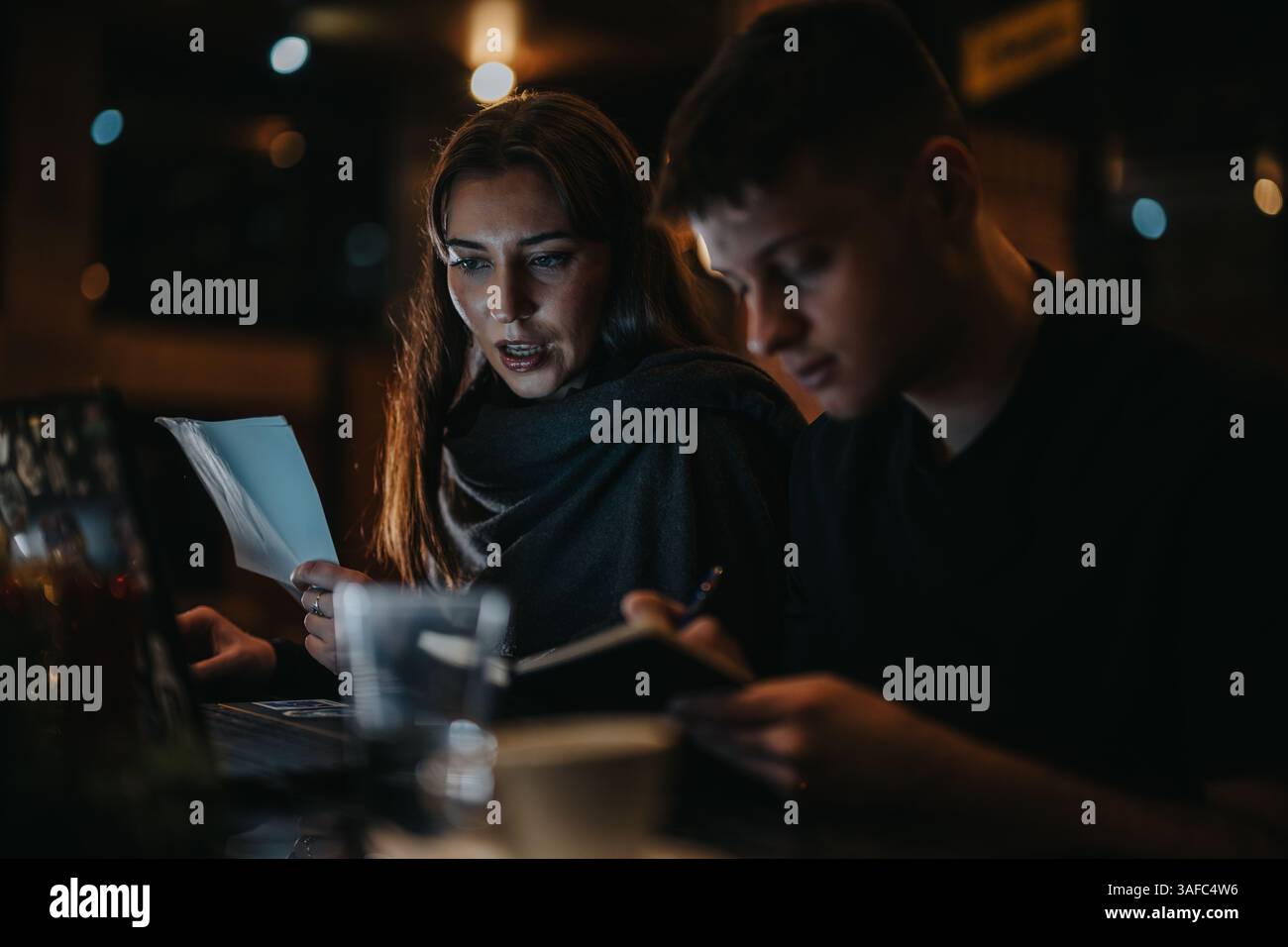 Two individuals collaborating on a project under ambient lighting in a ...