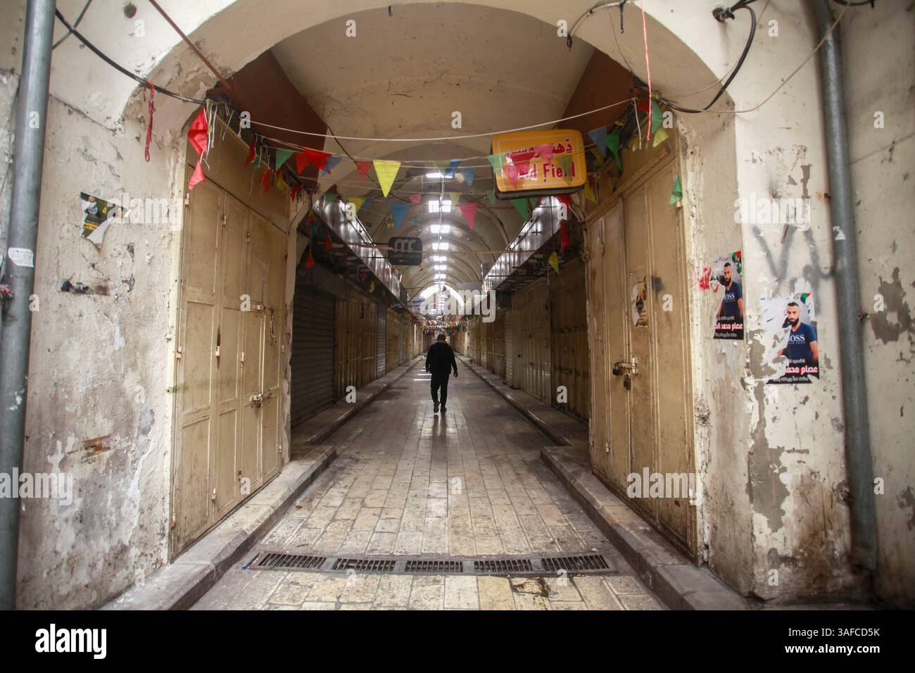A Palestinian walks past a closed market in the Al-Qasaba neighborhood ...