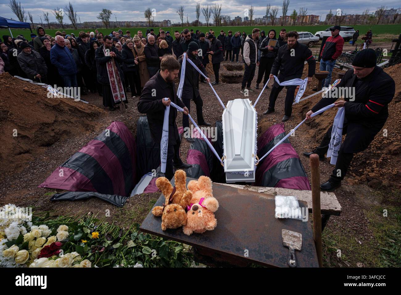Funeral workers bury coffins of children Danylo Nikittskyi, 15, and Alina Kutsenko, 15, killed ...