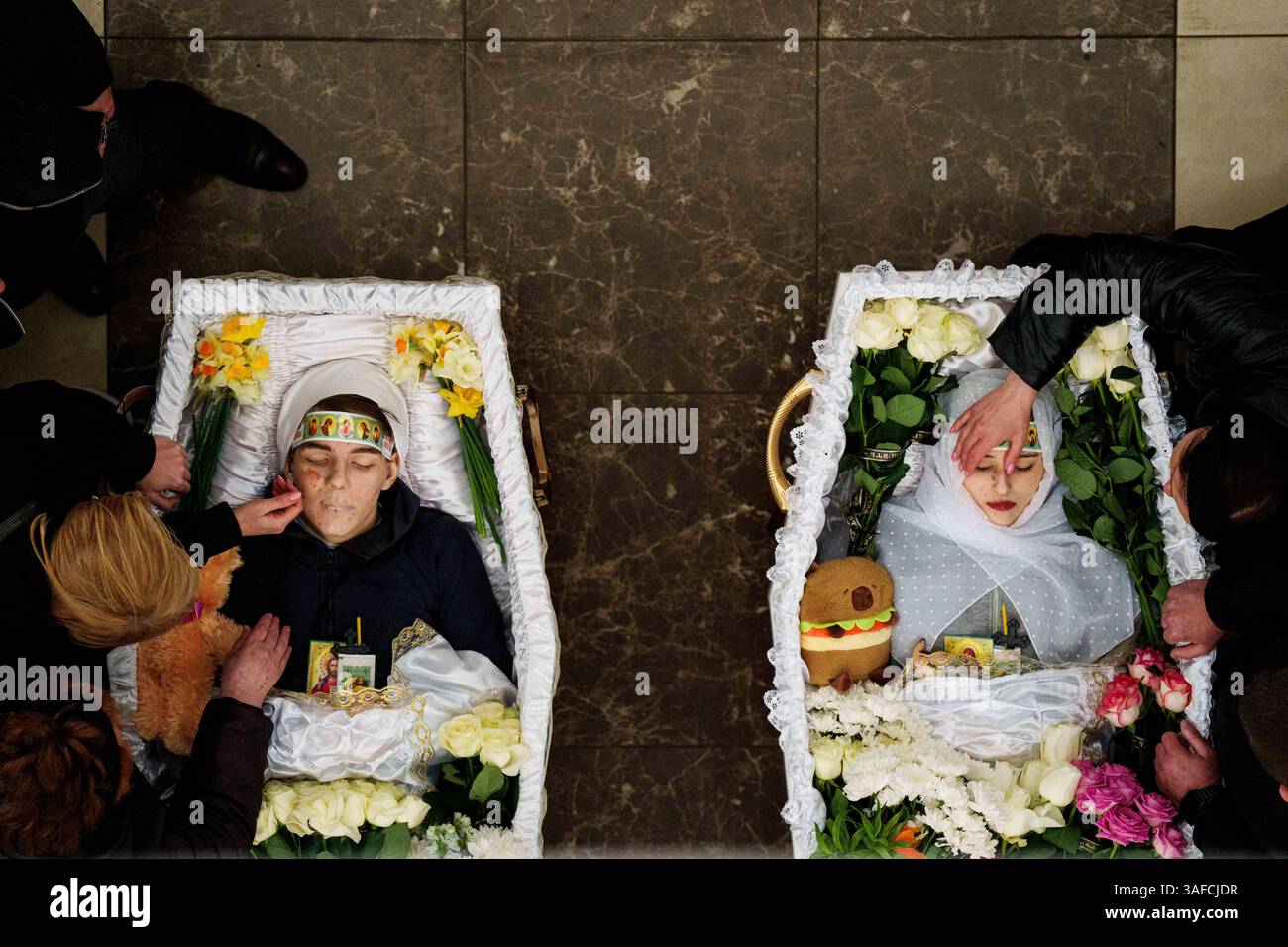 Mothers cry at the coffins of their children Danylo Nikittskyi, 15, left, and Alina Kutsenko, 15 ...