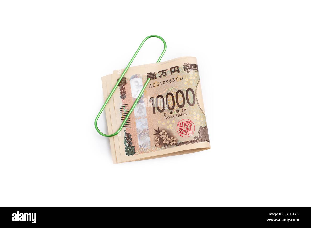 Ten thousands yen bank notes held by a green metal clip on a white ...