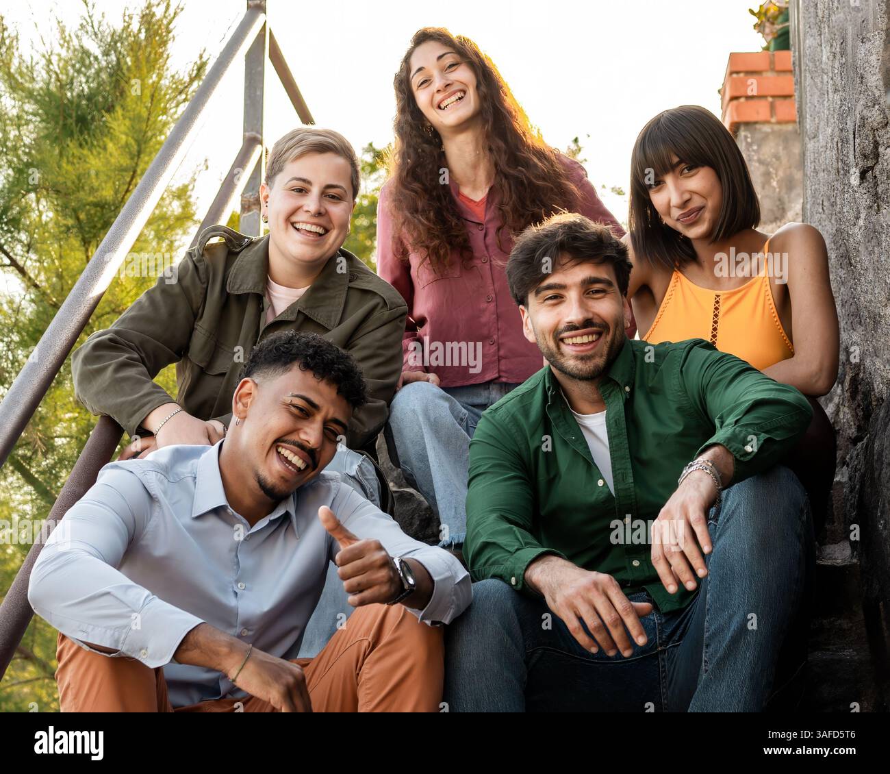 A diverse group of friends smiling and posing at the camera on outdoor ...