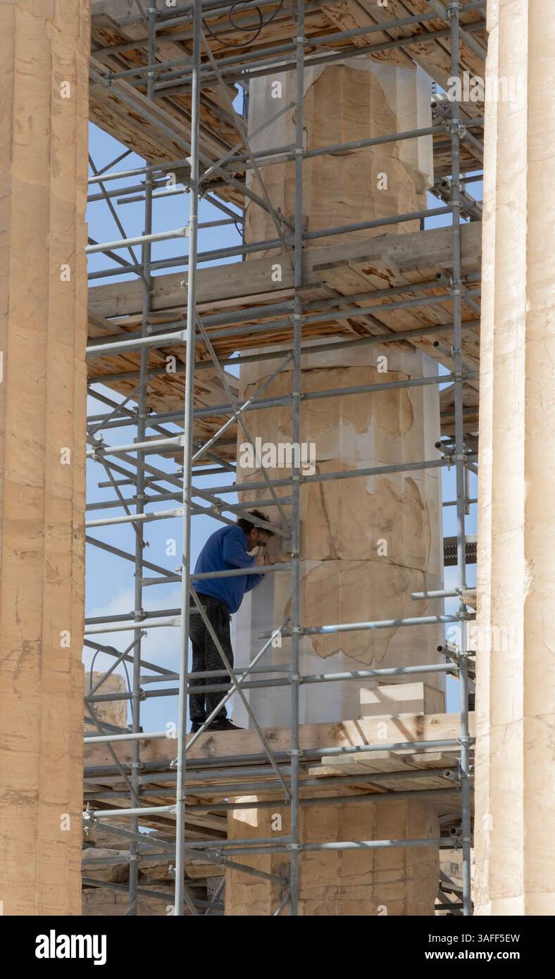 A sculptor standing on scaffolding works on one of the columns of the ...