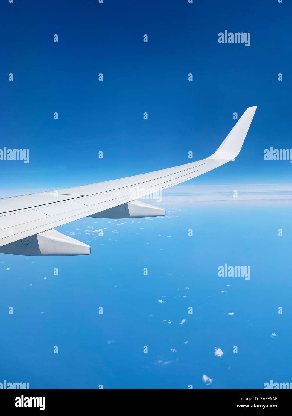 Flying above the ocean - window seat view. White airplane wing against ...