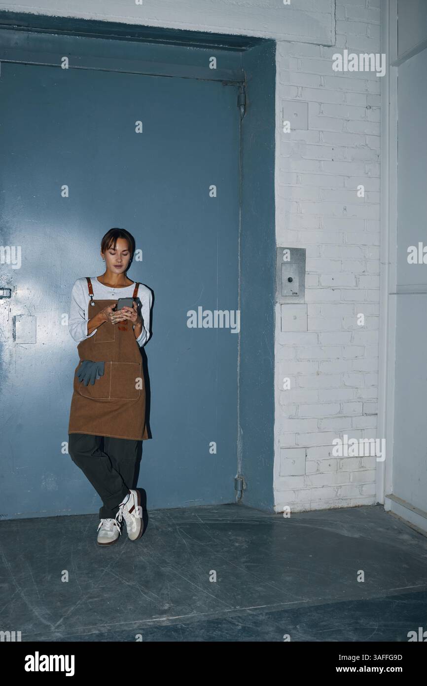 Female Worker Using Phone In Factory Stock Photo - Alamy