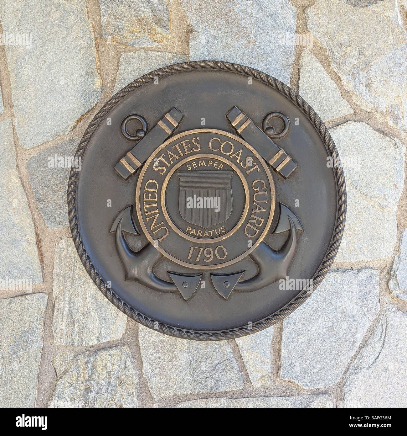 Bronze plaque of US Coast Guard emblem or crest on natural stone wall ...