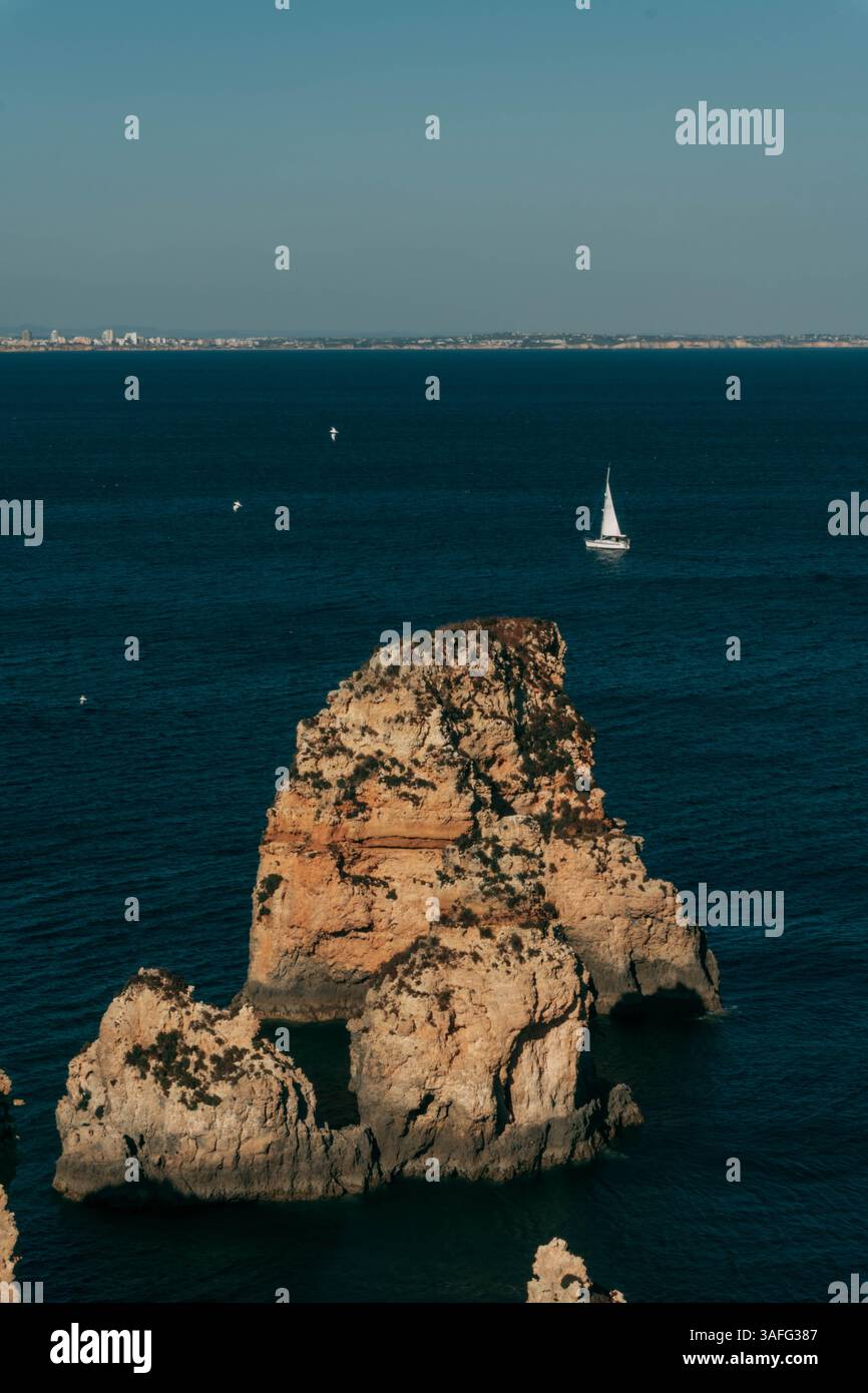 Sailboat gliding past stunning rock formations in Lagos, Portugal—where ...