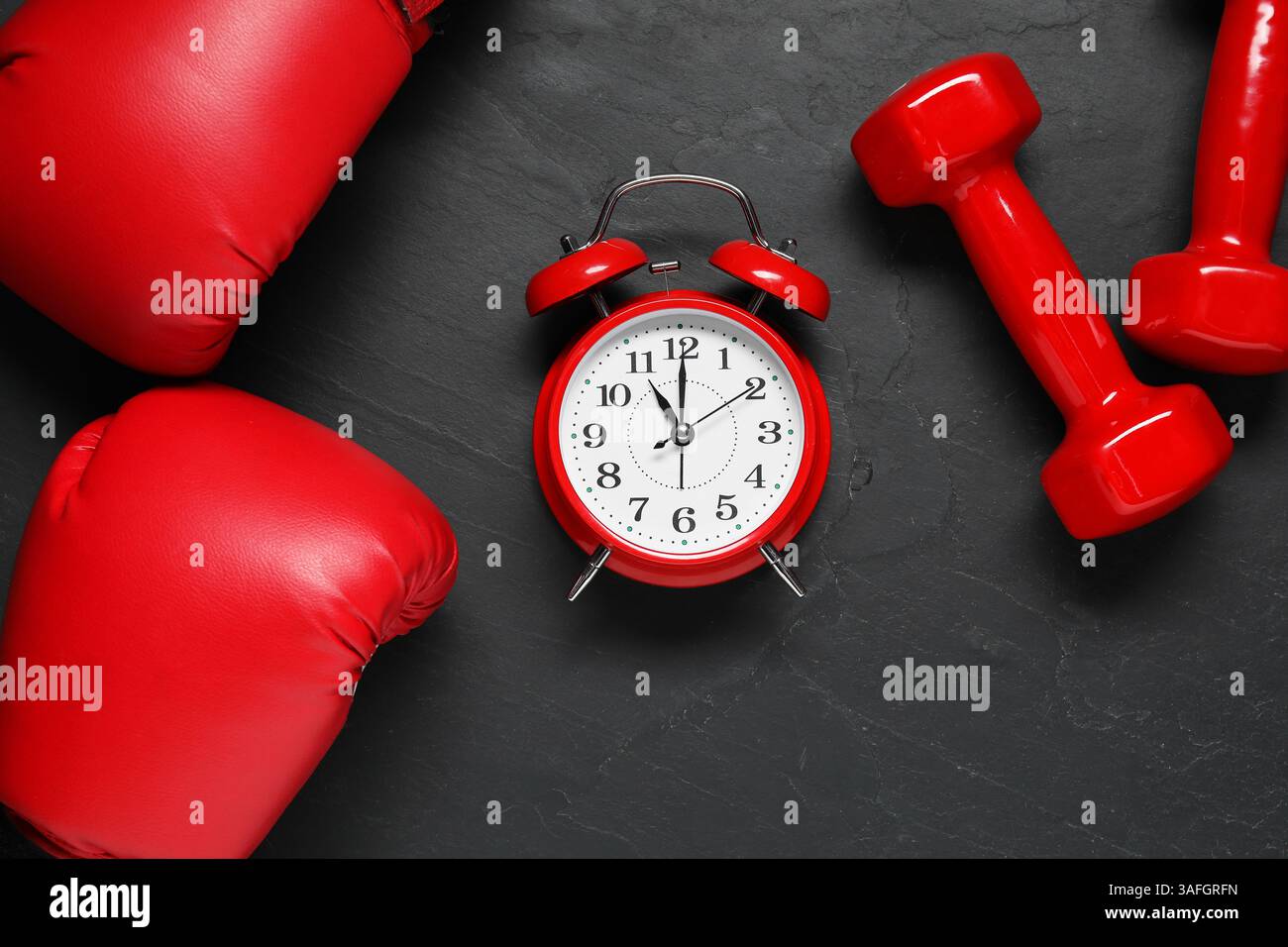 Alarm clock, boxing gloves and dumbbells on black background, flat lay ...