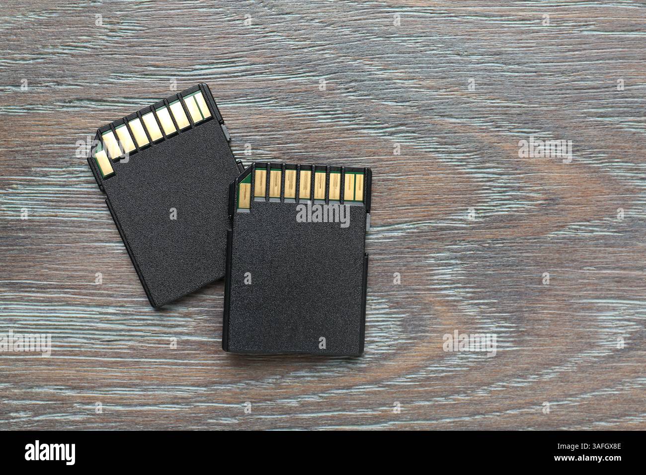 Two SD memory cards on grey wooden table, top view. Space for text ...