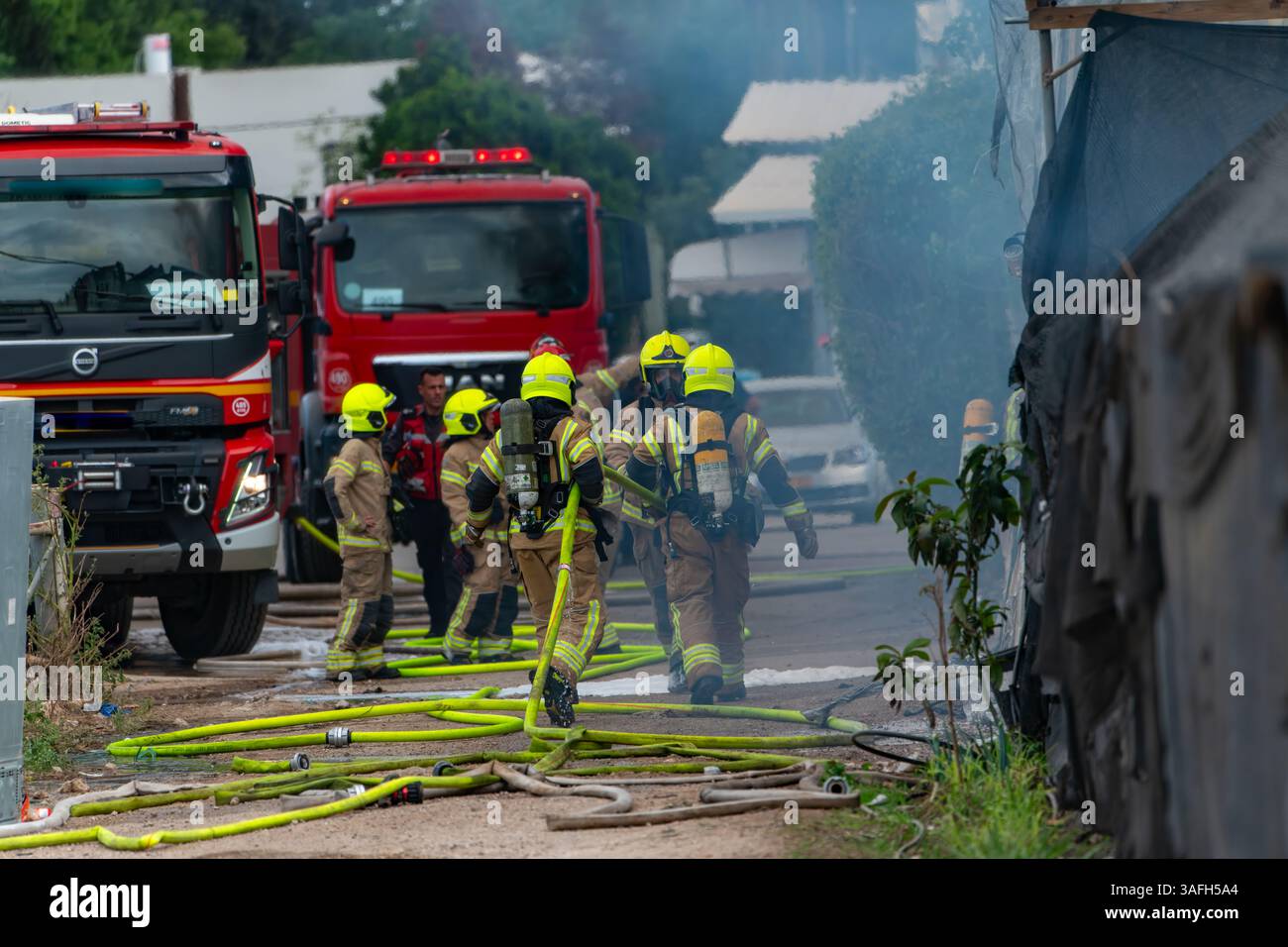 Firefighters extinguish a fire. Black smoke clouds and flames rise into ...