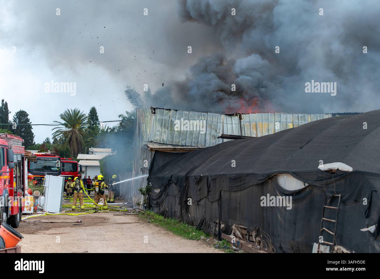 Firefighters extinguish a fire. Black smoke clouds and flames rise into ...