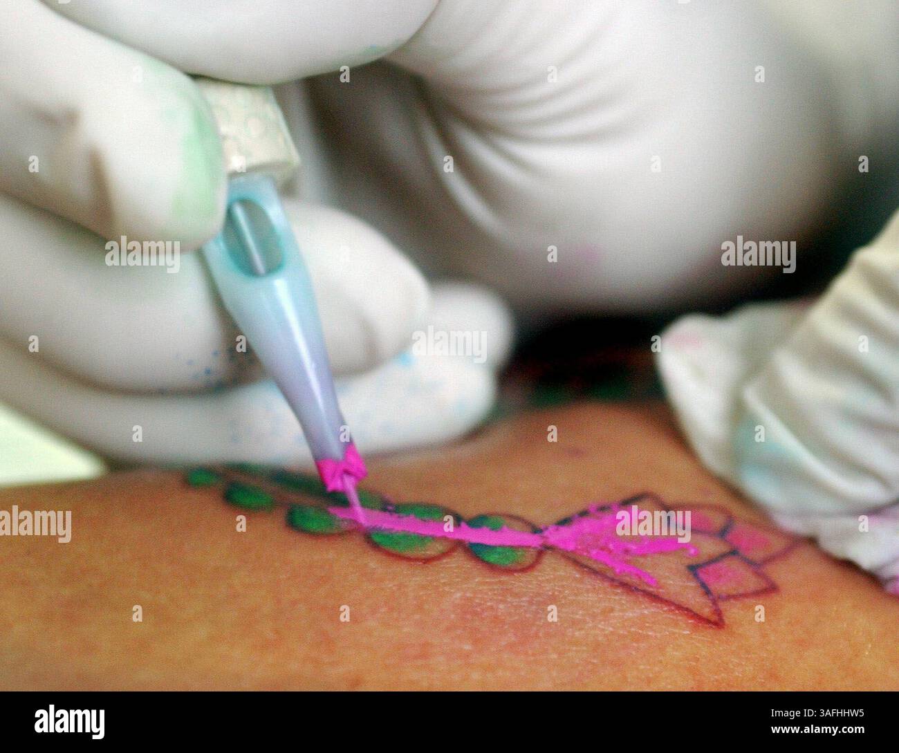 Tattoo Artist Paul Roe uses a single-use tattoo needle to fill in color ...