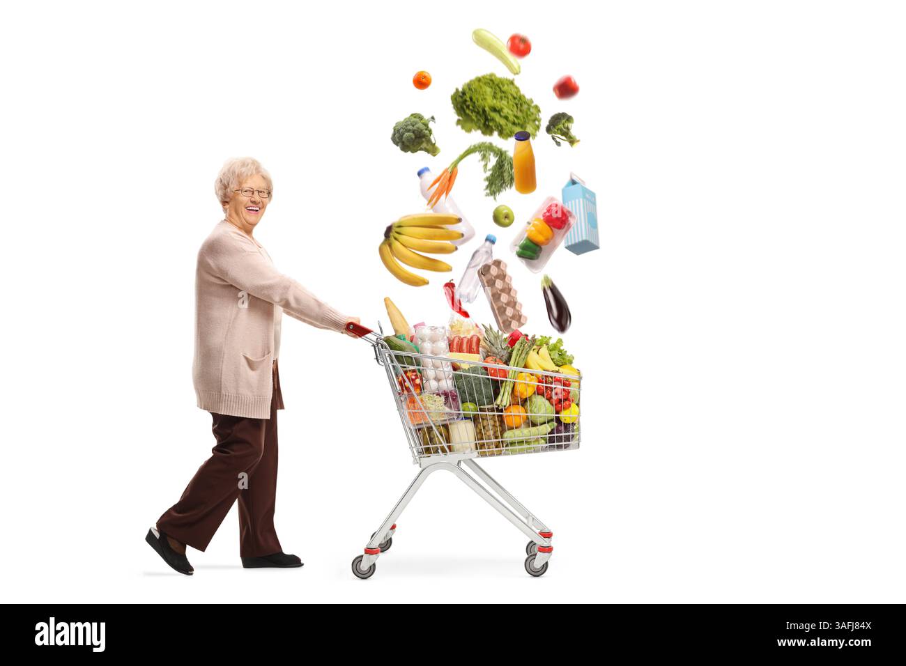 Senior woman pushing a shopping cart with falling food products ...