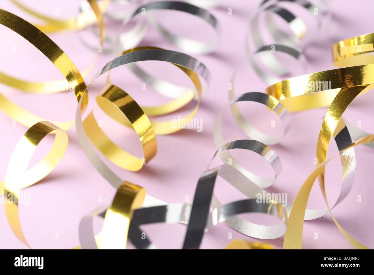 Shiny serpentine streamers on lilac background, closeup Stock Photo - Alamy