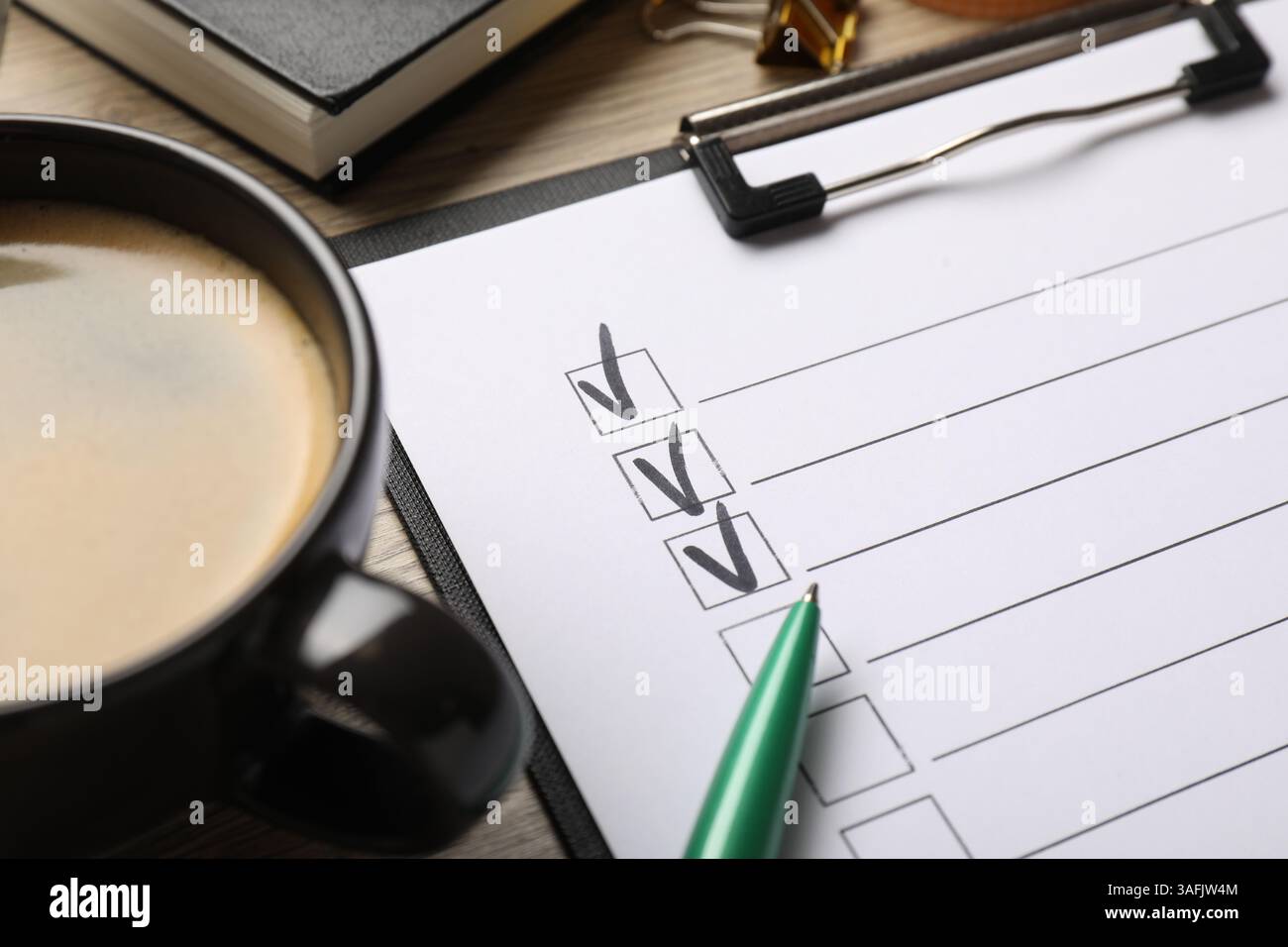Checklist with marked checkboxes, stationery and coffee on table ...