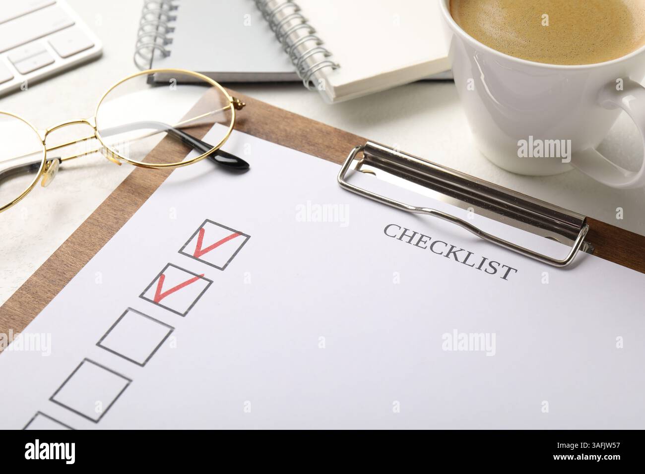 Checklist with marked checkboxes, stationery, glasses and coffee on ...