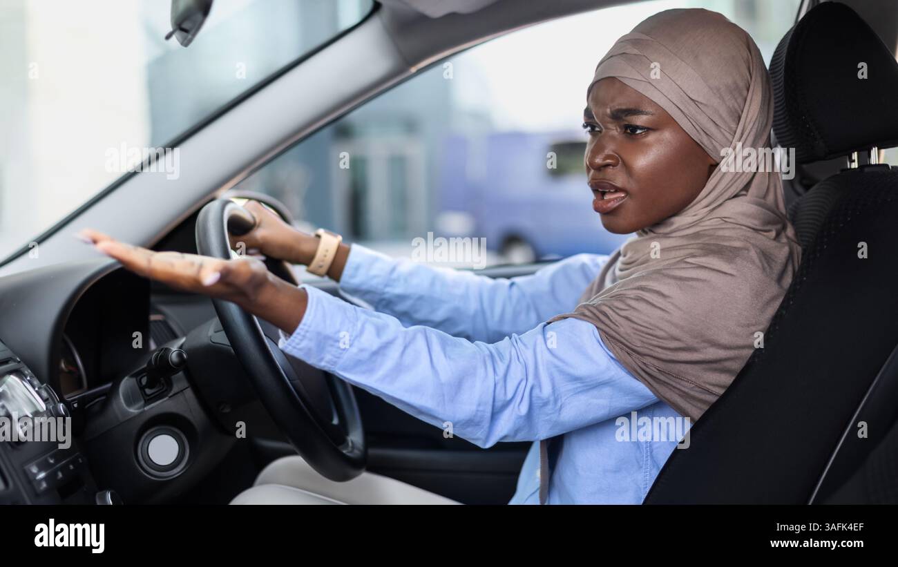Stressed black muslim woman arguing with someone while driving car ...