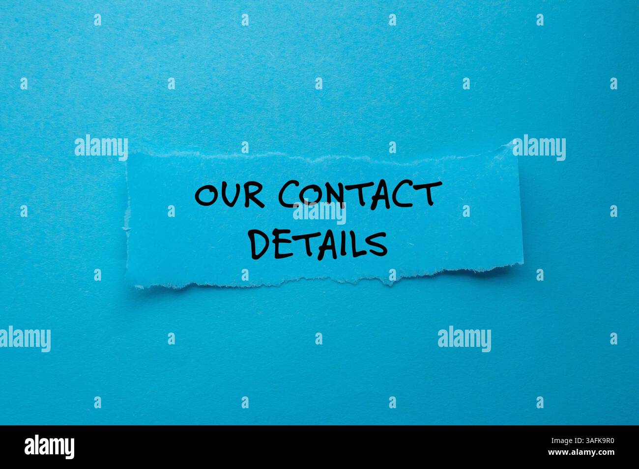 Our contact details message written on ripped torn paper piece on blue background. Conceptual ...