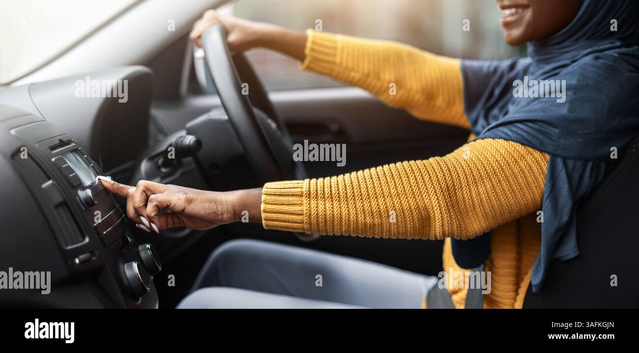 Positive black religious lady in hijab listening radio in car, changing ...