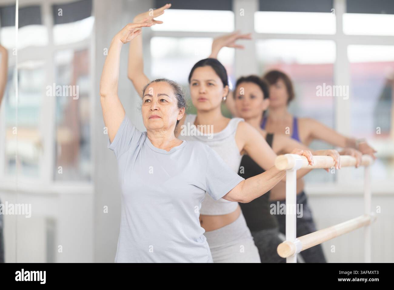 Group of women stand in fourth position at barre Stock Photo - Alamy