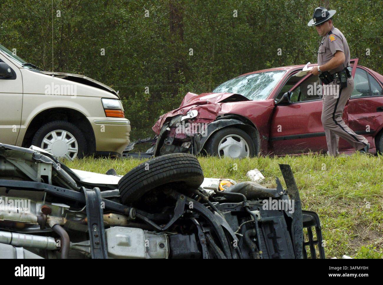 A Florida Highway Patrol trooper looks at the scene of a four vehicle ...