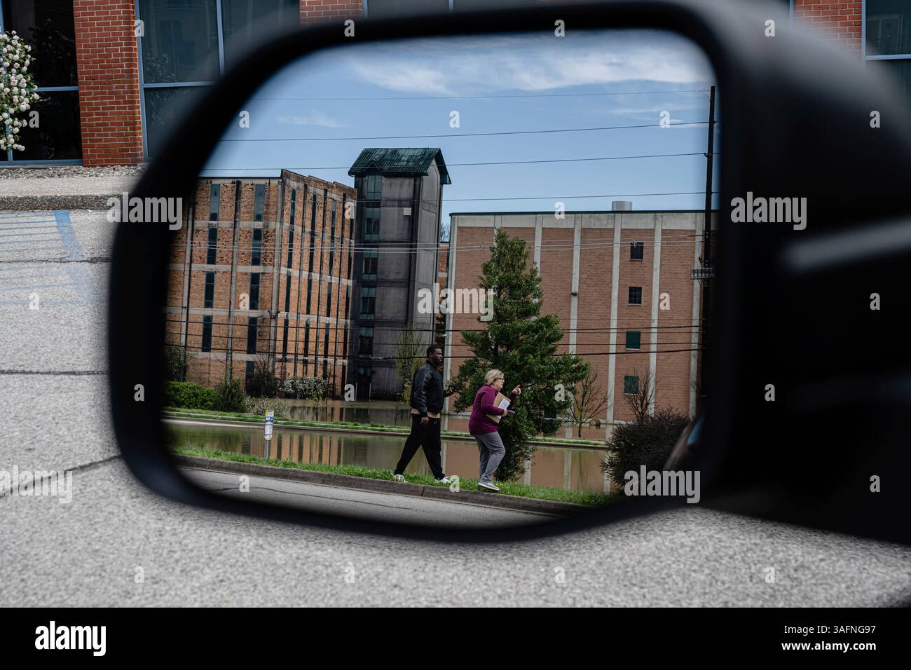 In a reflection, community members walk near the flooded Buffalo Trace ...