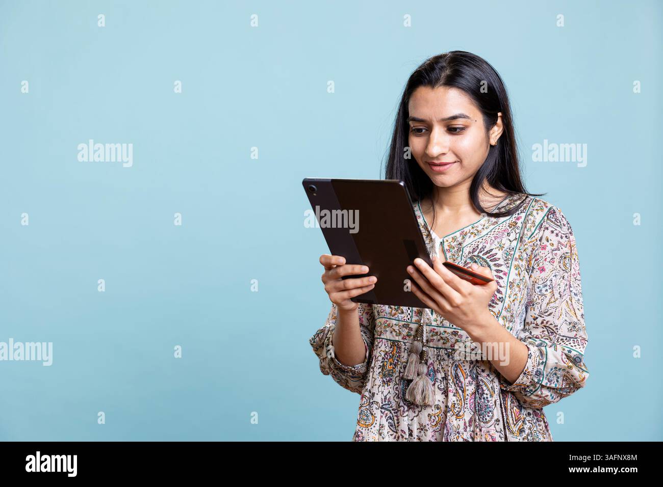 Indian person excited to purchase stuff adding payment method on website with her tablet ...