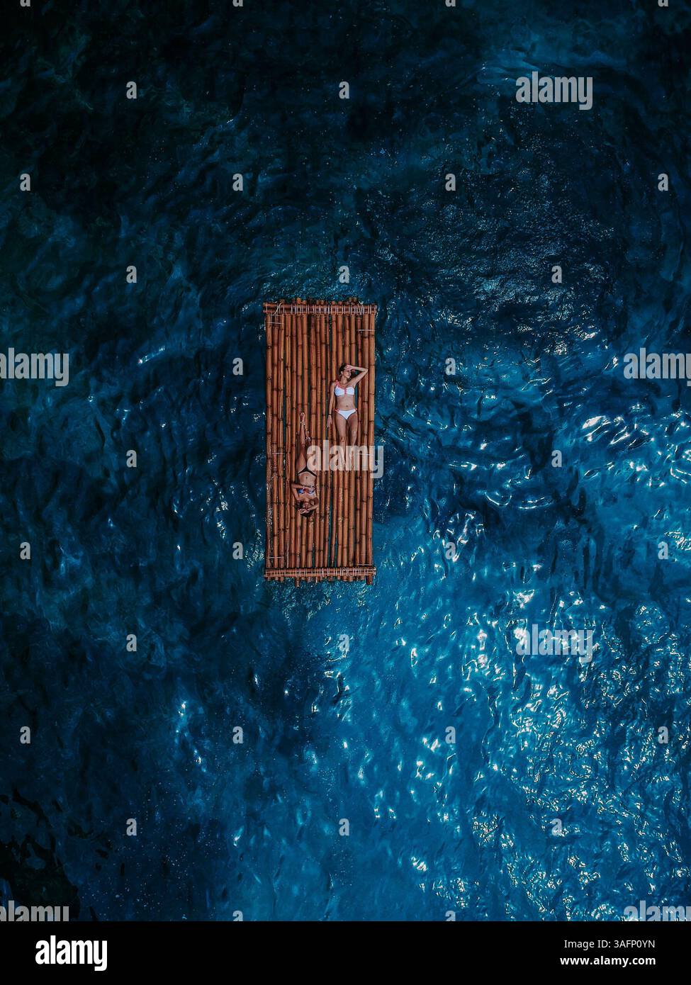 Aerial view of a bamboo raft floating on the deep blue ocean with two ...