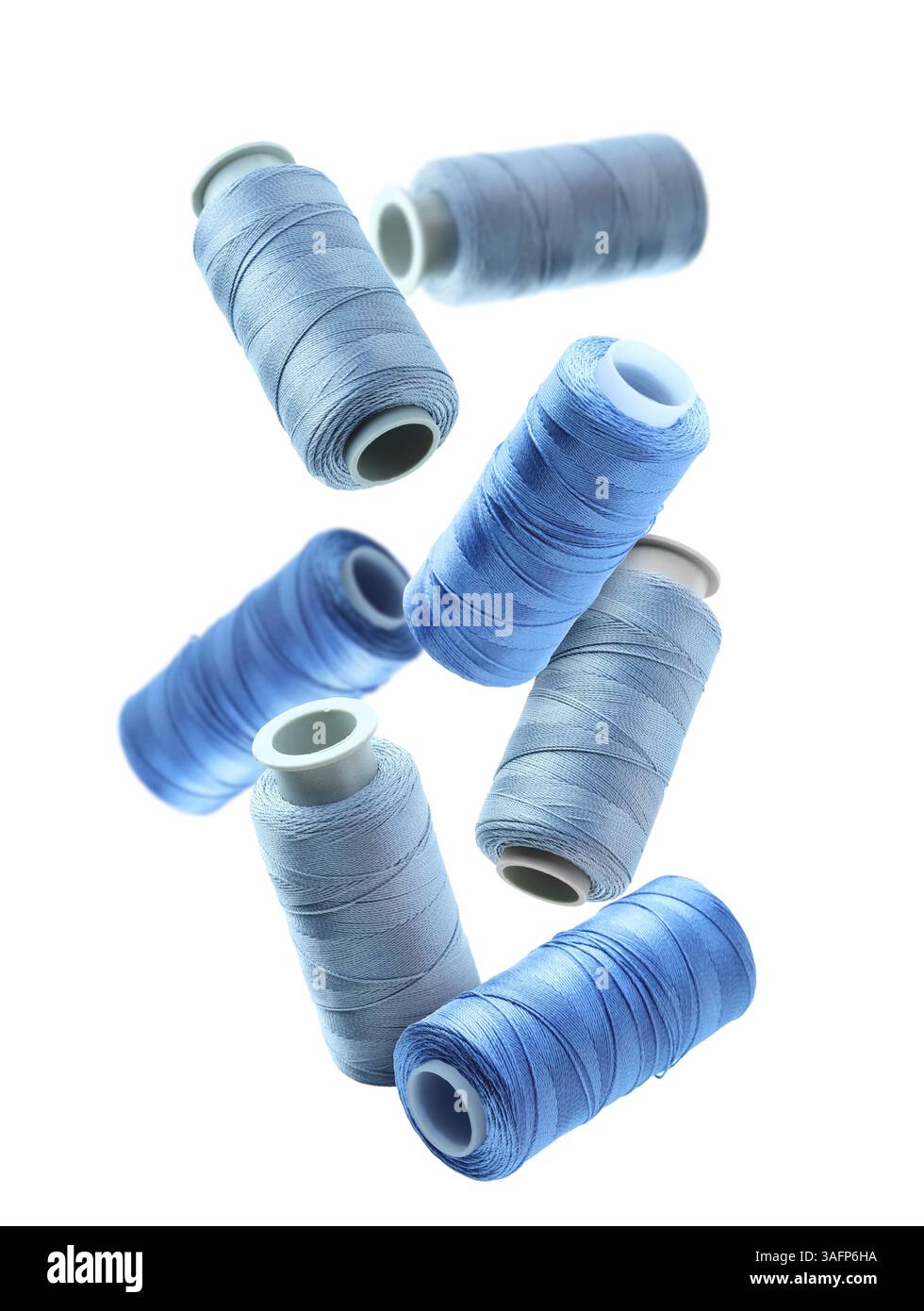 Many sewing threads in different shades of blue flying on white ...