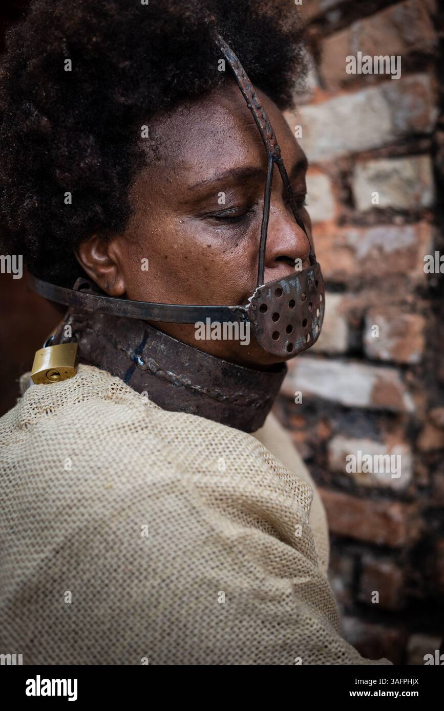 Black woman dressed as a slave, chained with an iron mask on her mouth ...