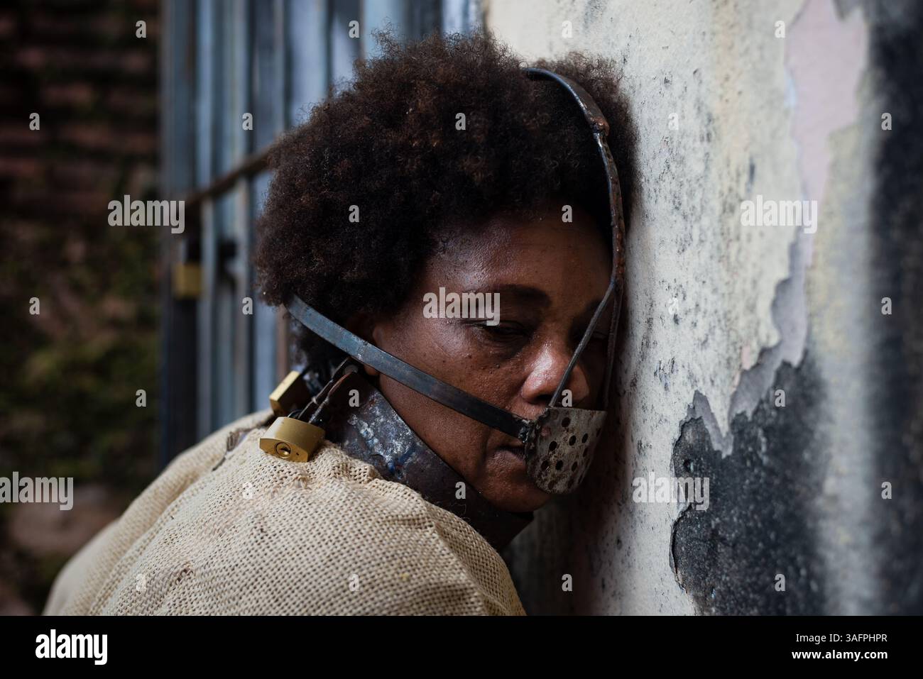 Black woman dressed as a slave, with an iron mask over her mouth and ...