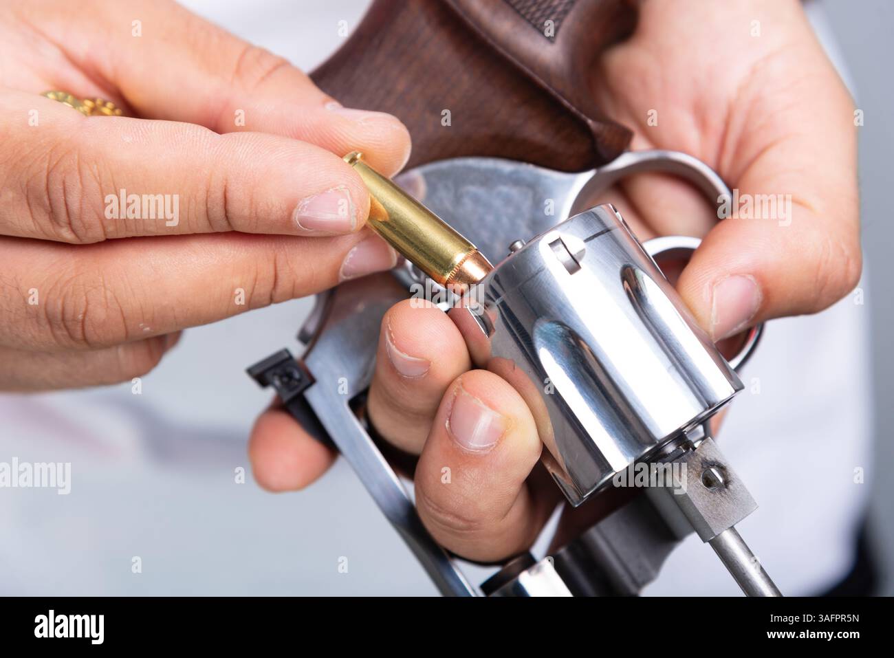 Detail of a shooting instructor loading a bullet into a silver revolver ...