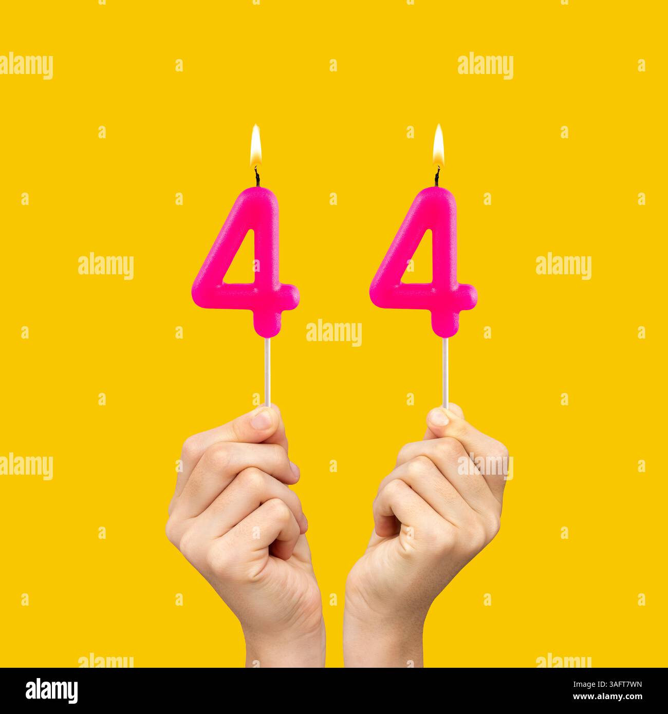Hands holding birthday candles with number 44 - Yellow background Stock ...