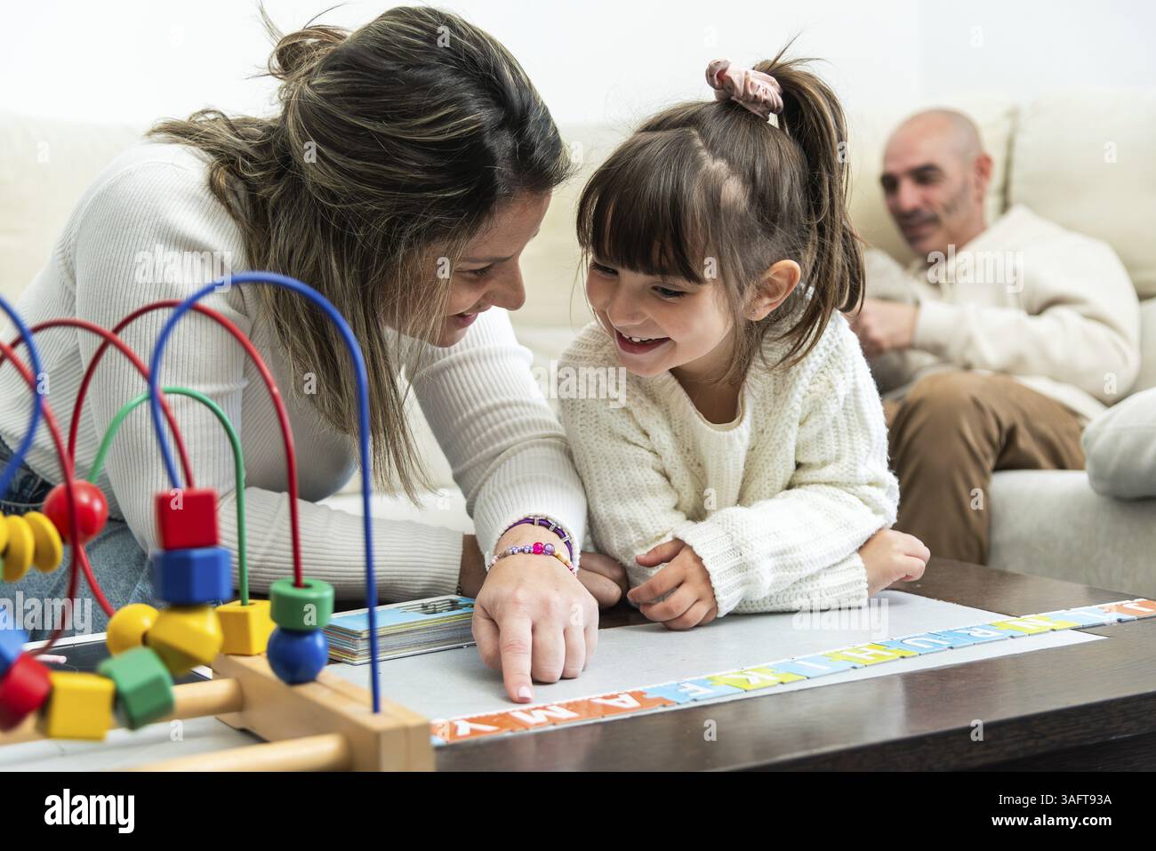 Happy family playing with alphabet puzzle, mother teaching daughter ...