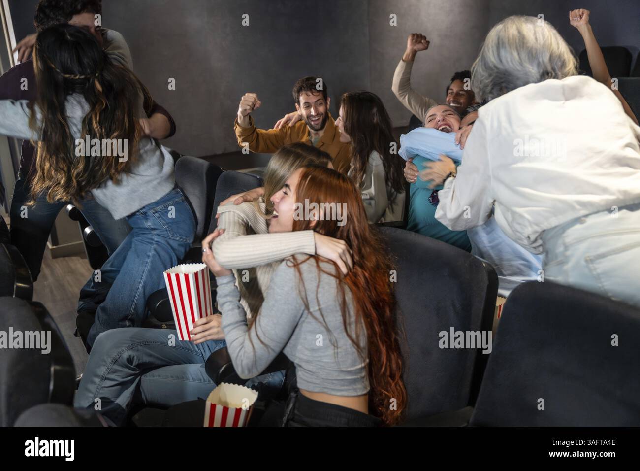 Enthusiastic friends are enjoying a movie at the cinema, hugging ...