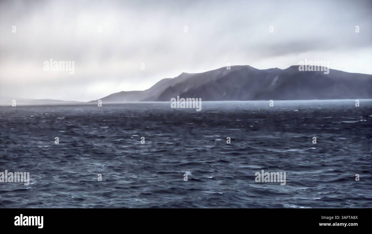 Haze-covered sea under a gloomy sky with distant land masses, Chile ...