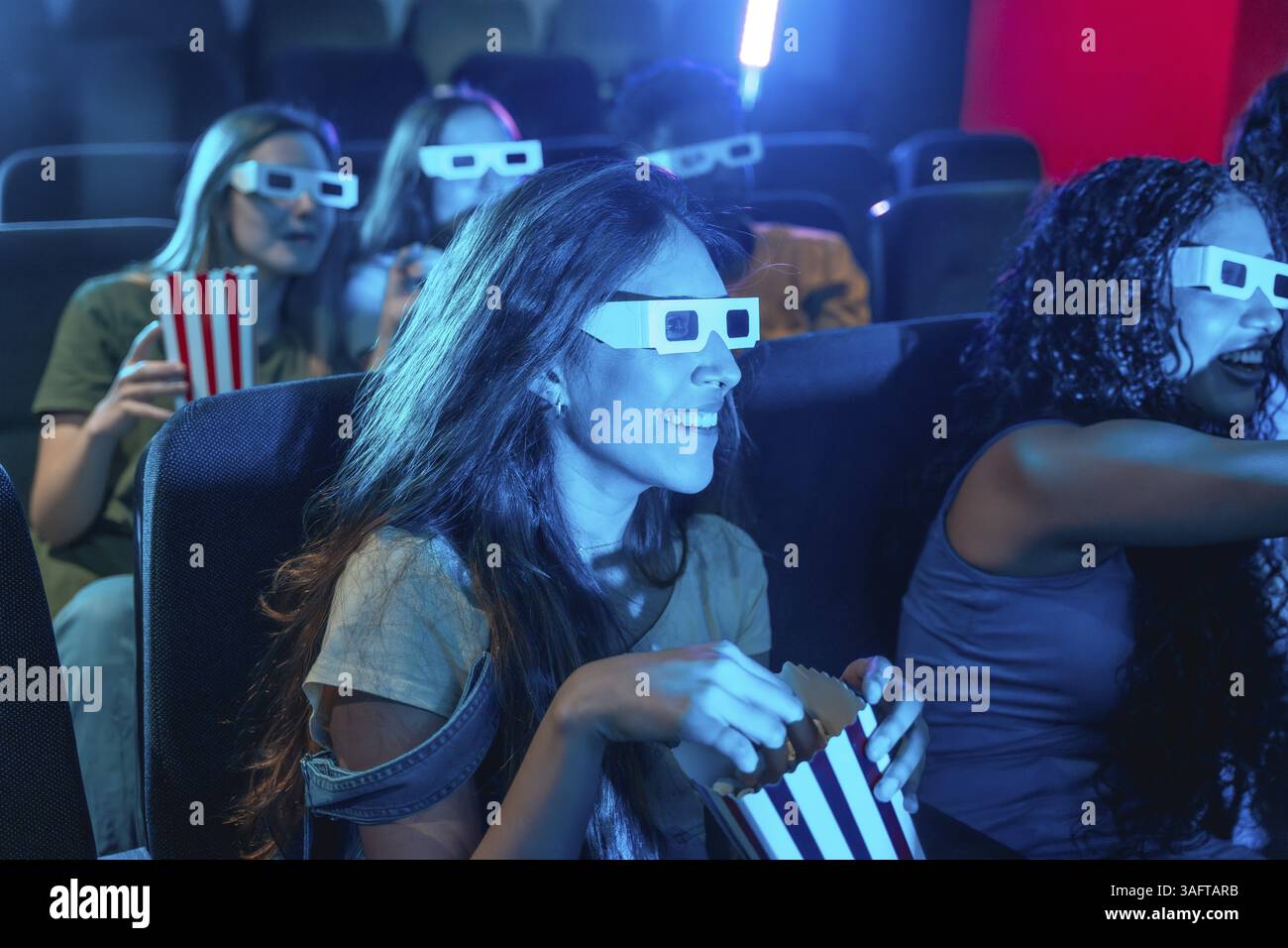 Group of friends wearing 3d glasses watching a movie and eating popcorn ...